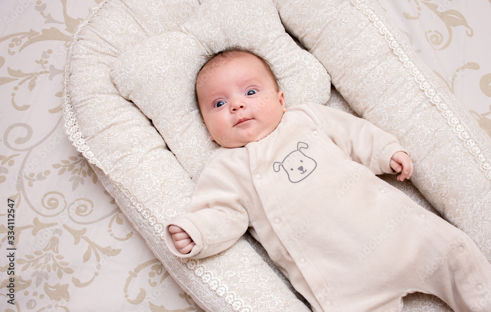 portrait of a newborn little girl lying in a pastel cocoon and laughing ...