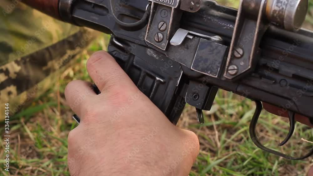 Close-up of a male hand inserting a magazine with ammunition into a ...
