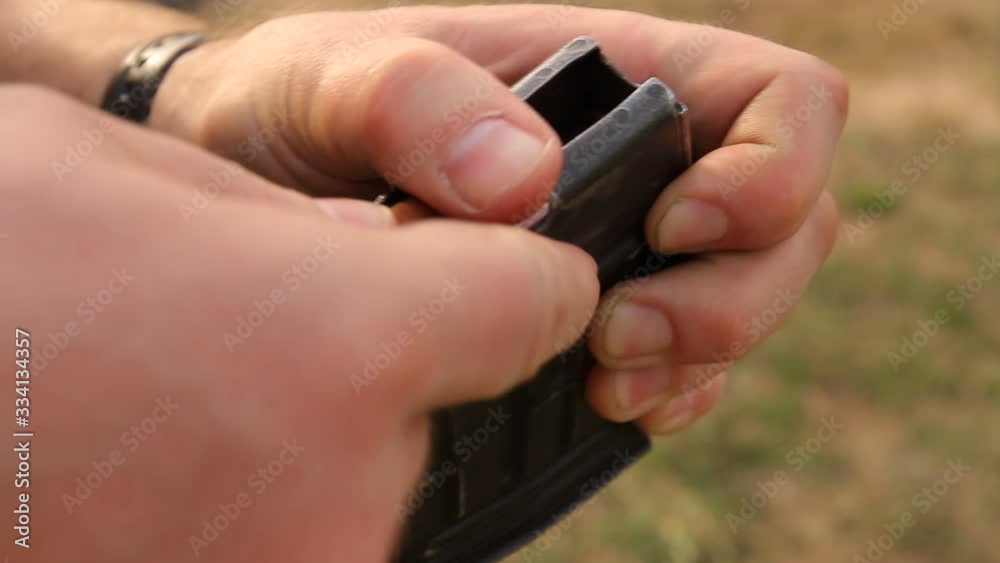 A man inserts live ammunition into a sniper rifle magazine and then ...