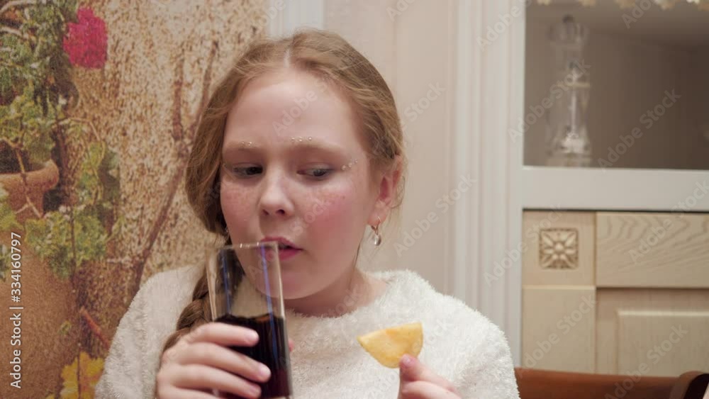 Portrait teenager girl eating potato chips and drinking soft drink in ...