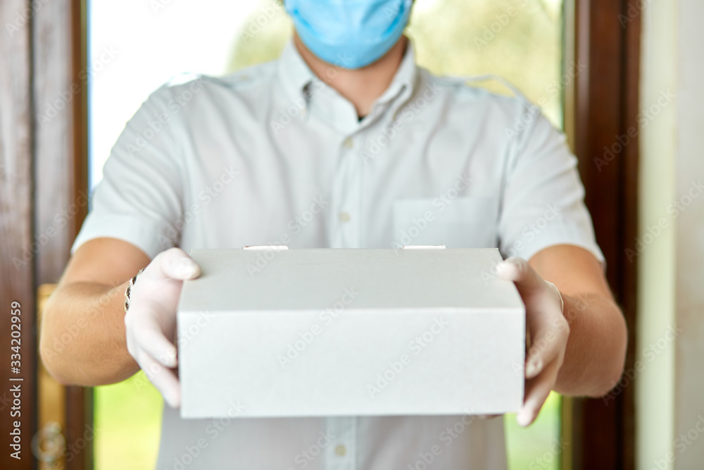 Courier, delivery man in medical latex gloves and mask safely delivers ...
