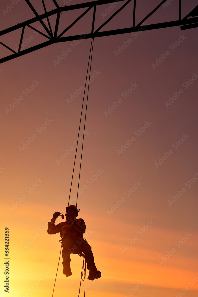 Silhouette of a construction worker hanging on safety harness on a ...