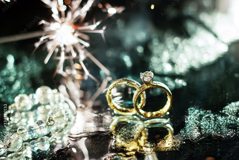 Wedding rings on a dark background with splashes of water and a burning ...