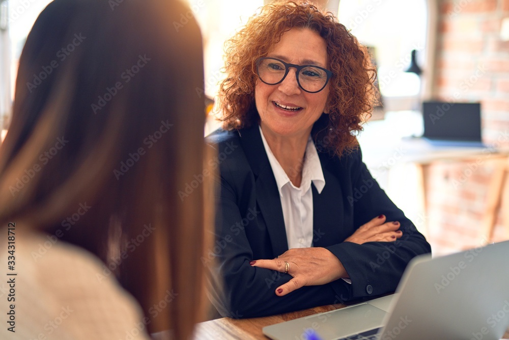 Two beautiful businesswomen smiling happy and confident. Sitting with ...