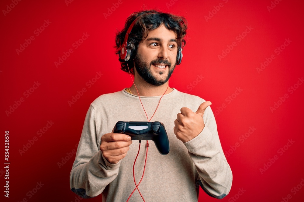 Young gamer man with curly hair and beard playing video game using ...