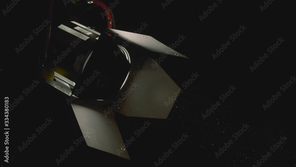 Tiny dust particles moving and floating in the beam of a spotlight in a ...