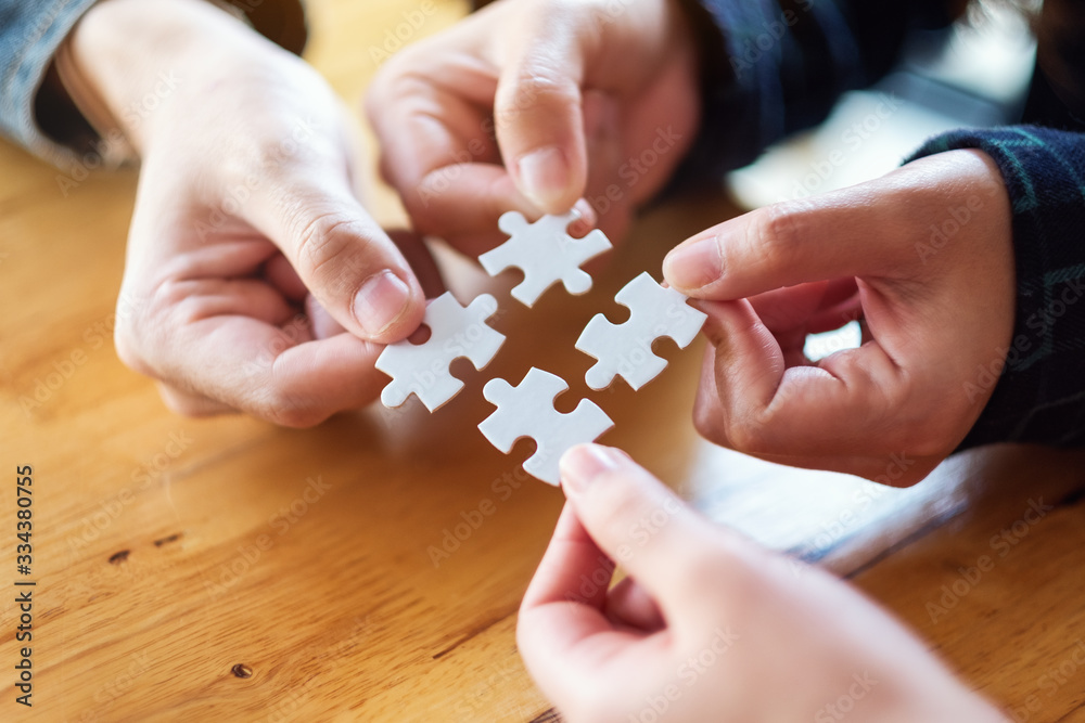 Closeup image of a group of people holding and putting a piece of white ...