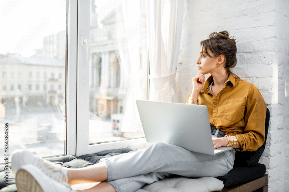 Young woman dressed casually working on laptop while sitting on the ...