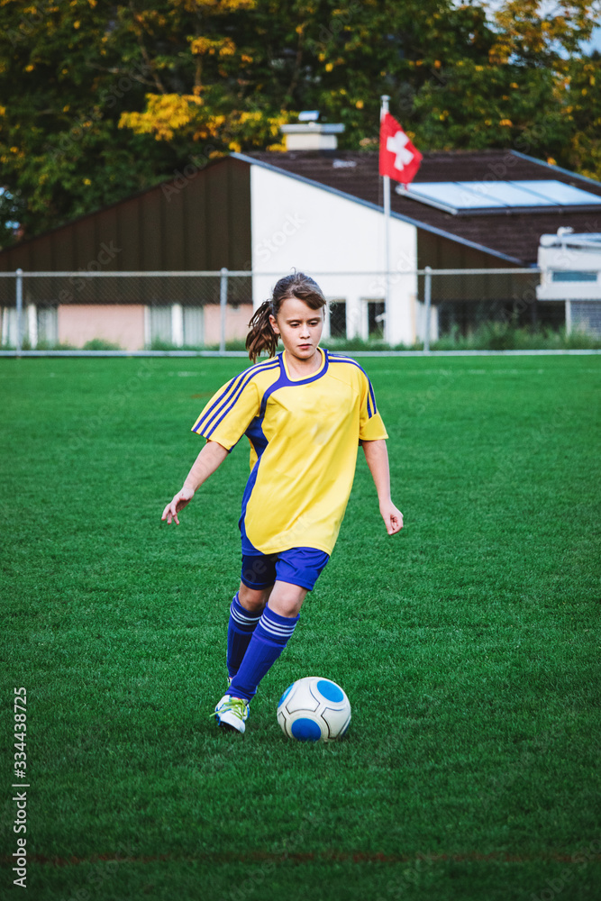 Young girl playing football at stadium with local girls football team ...