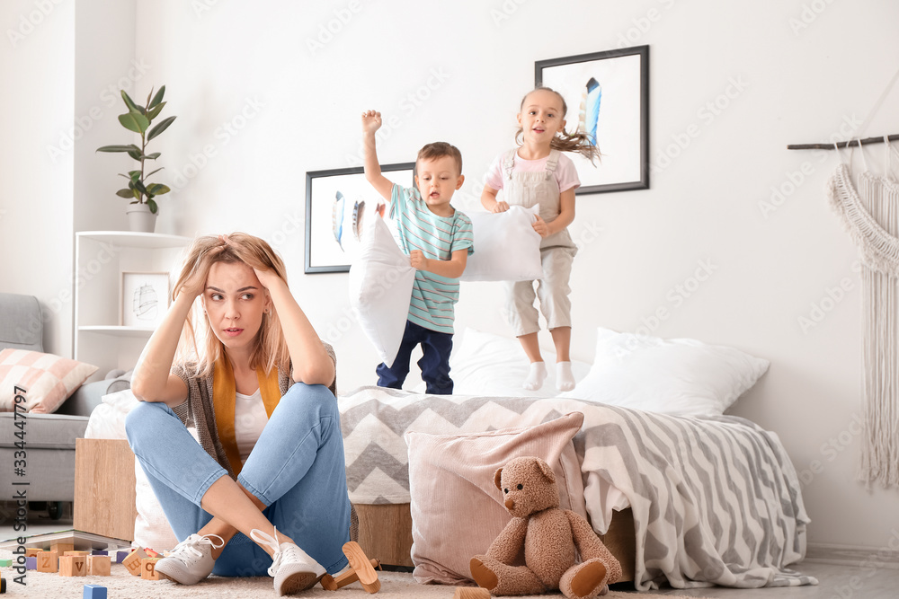 Helpless nanny and naughty little children playing in bedroom Stock ...