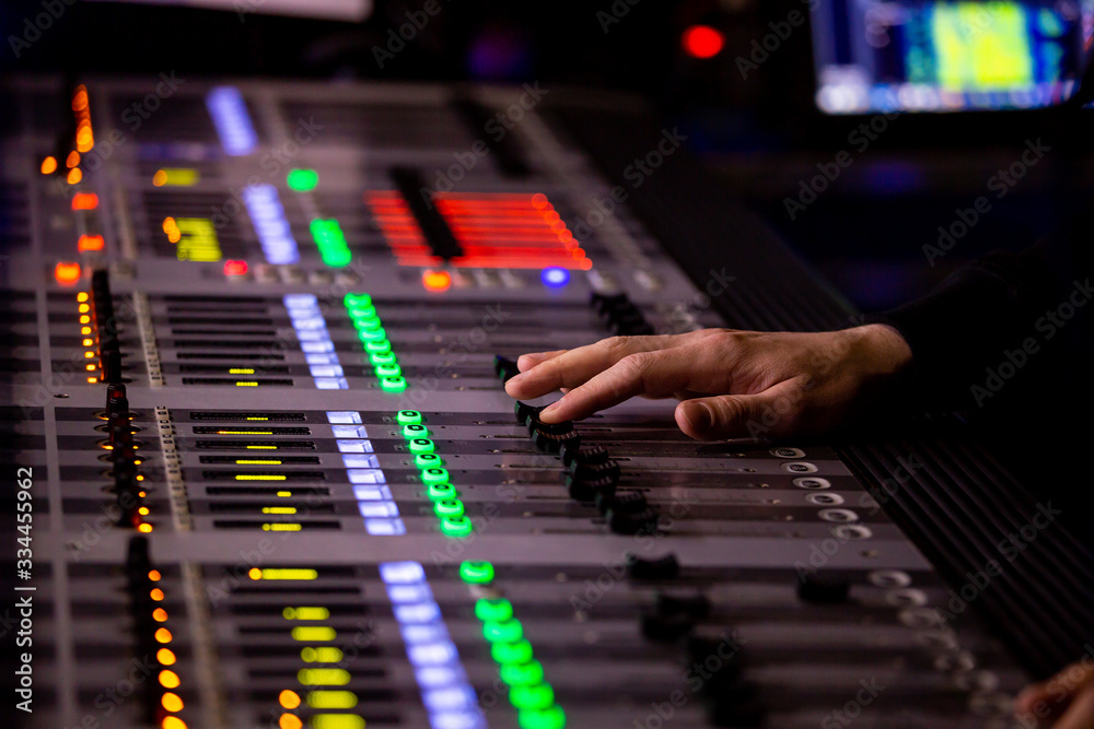 Sound engineer controls the settings on the mixing console panel in ...