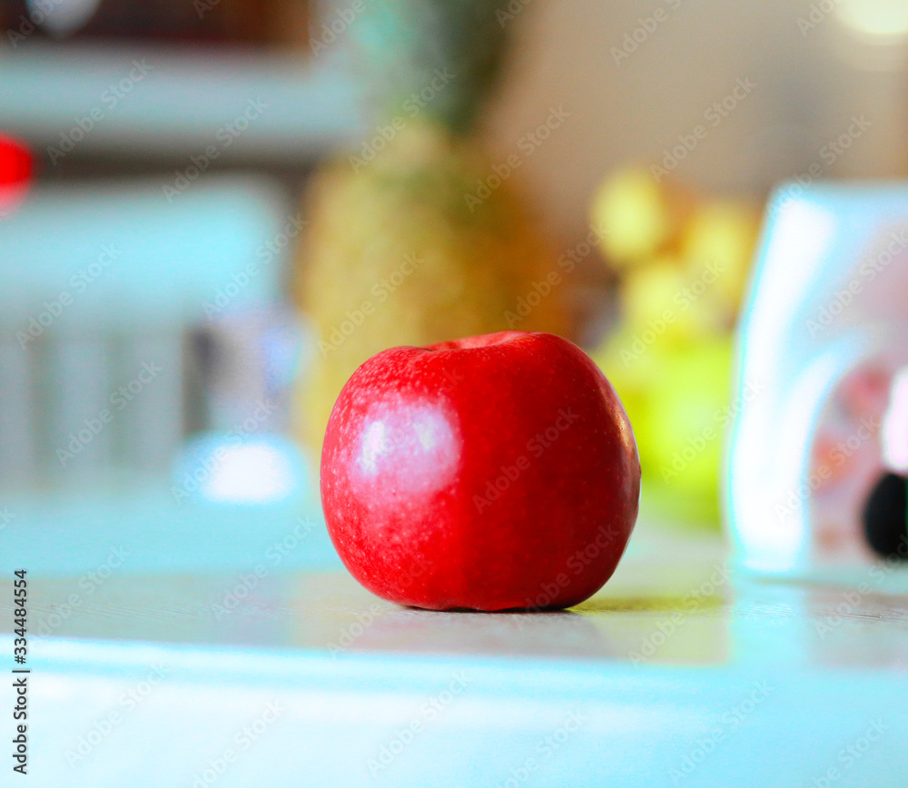 Red apple and diverse fruits on a table in a modern kitchen. Useful ...