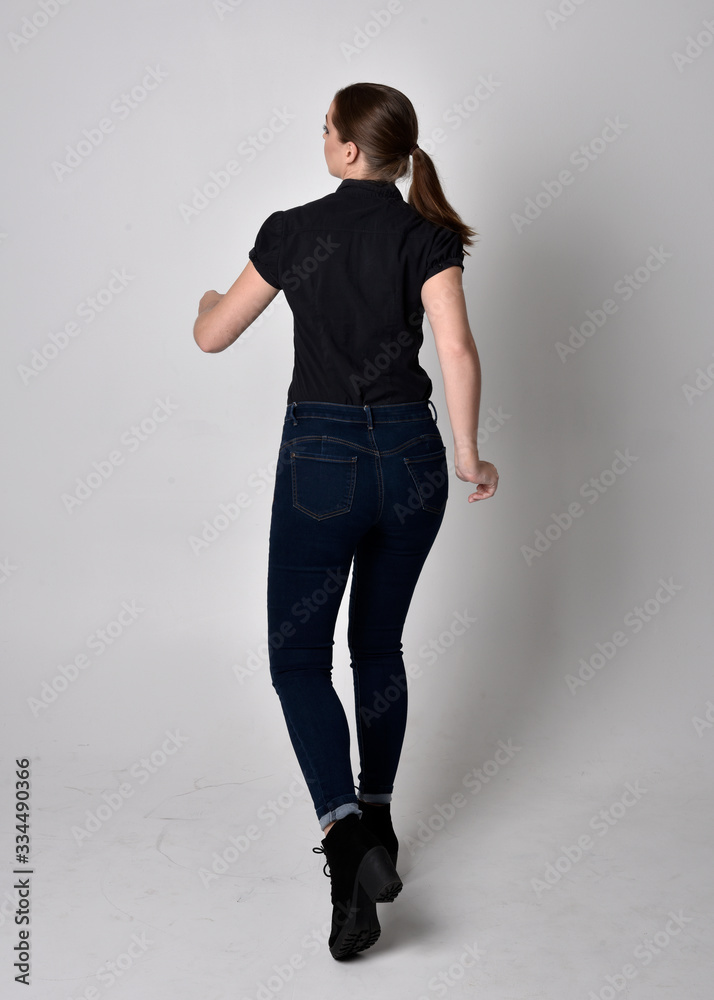 Portrait of a pretty brunette girl with ponytail, wearing jeans boots ...