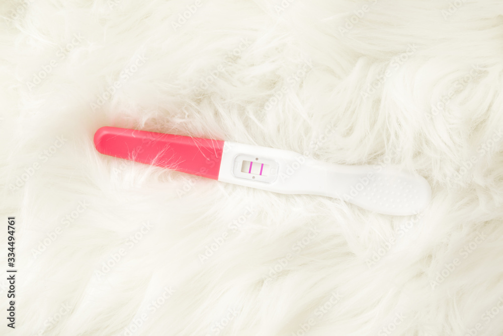 Pregnancy test with two stripes on white, soft, fluffy fur blanket ...