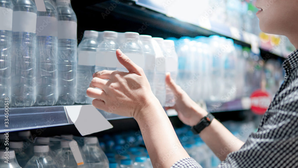 Male shopper picking pack of mineral water bottle from product shelf in ...