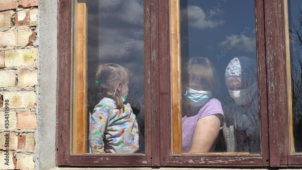 Window and family standing indoors. Family wearing masks. Pandemic and ...