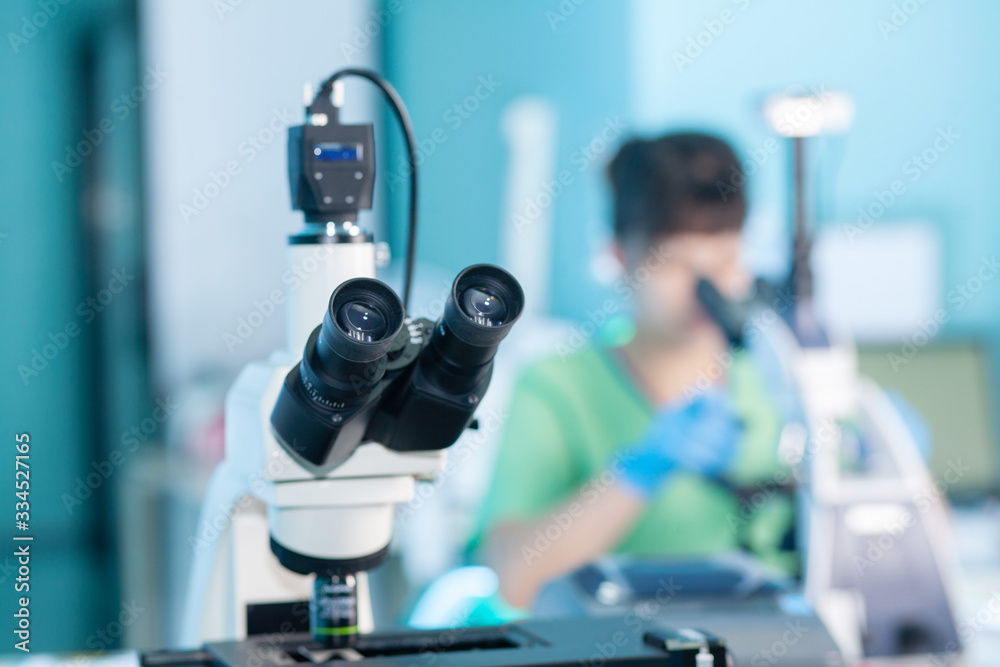 Female professional in uniform. Work with a light microscope in a ...