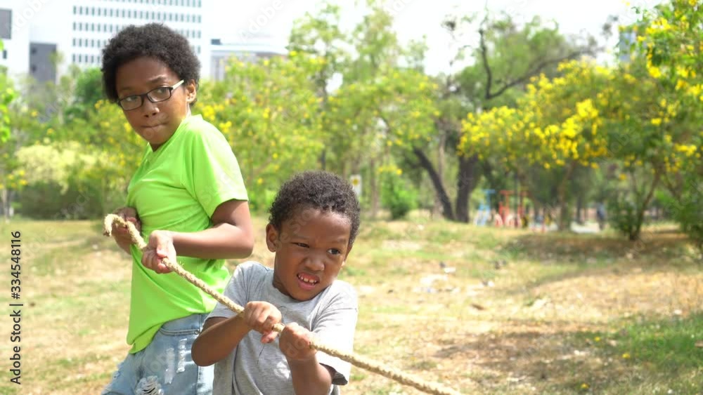 African American serious boy and girl pulling a rope together in tug of ...