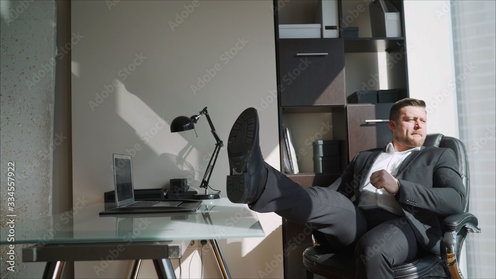 Businessman in his office throws legs on the table. An exhausted ...