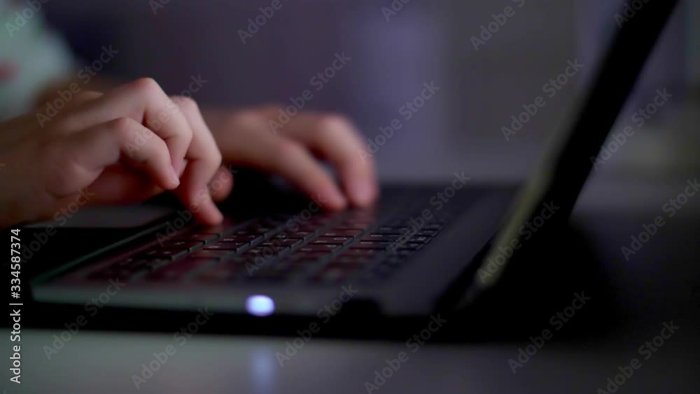 close-up, hands of a girl, a child are typing on a laptop keyboard ...