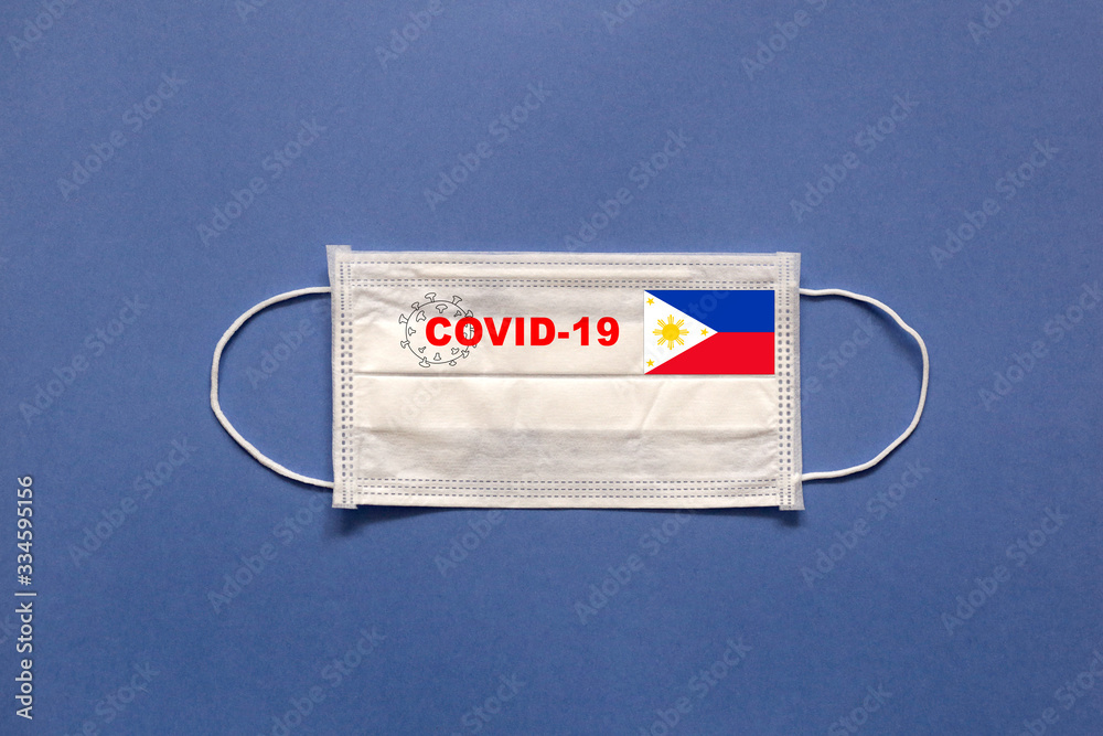 Flag of the Philippines and inscription COVID-19 on a medical mask on a ...