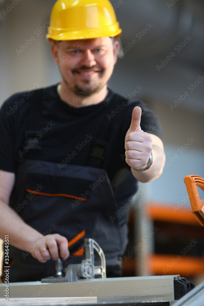 Smiling worker in yellow helmet show confirm sign with thumb up at arm ...