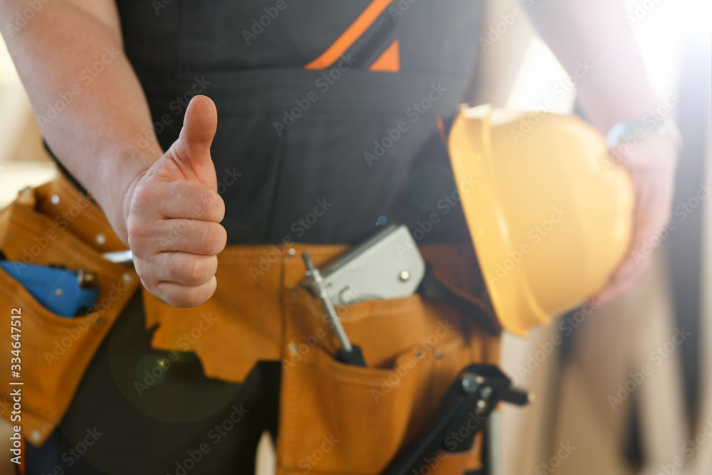 Hand of worker in yellow helmet show confirm sign with thumb up at arm ...