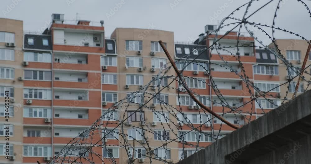 residential multi-storey building behind a concrete fence with barbed ...