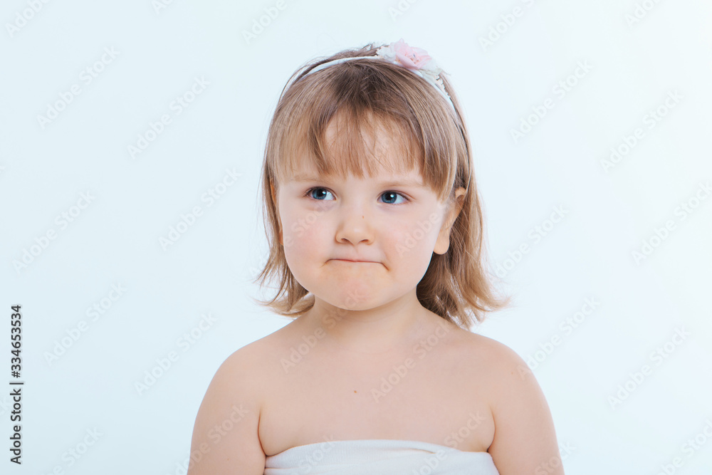 a little girl grimaces against a white background. The child is up to ...
