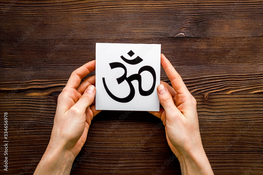 Om - Buddhist inner peace symbol - in hands on wooden desk top view ...