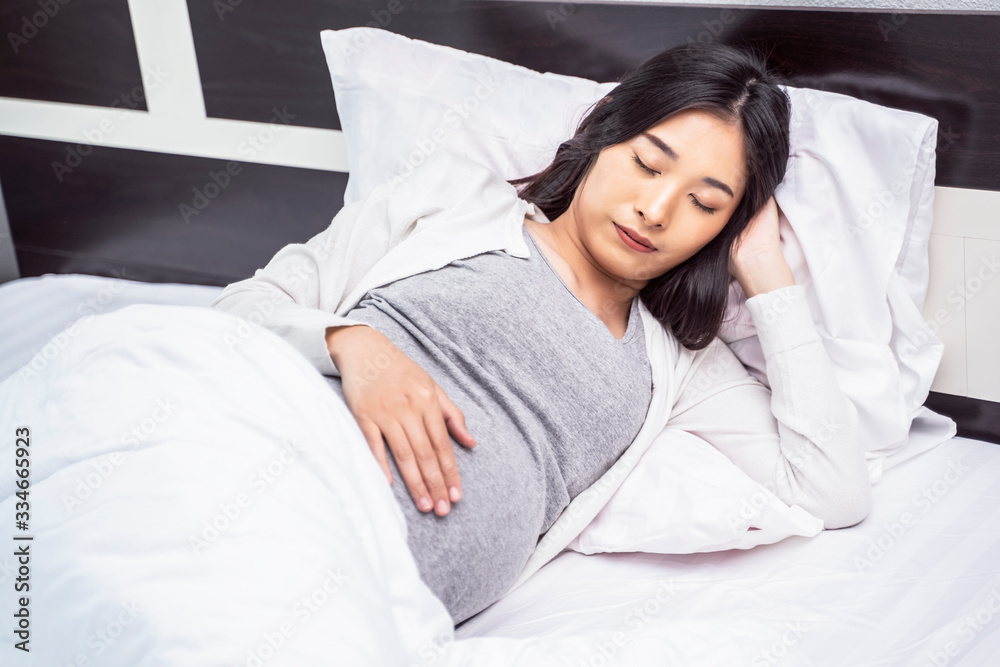 Beautiful asian pregnant woman laying down on bed sideways sleeping ...
