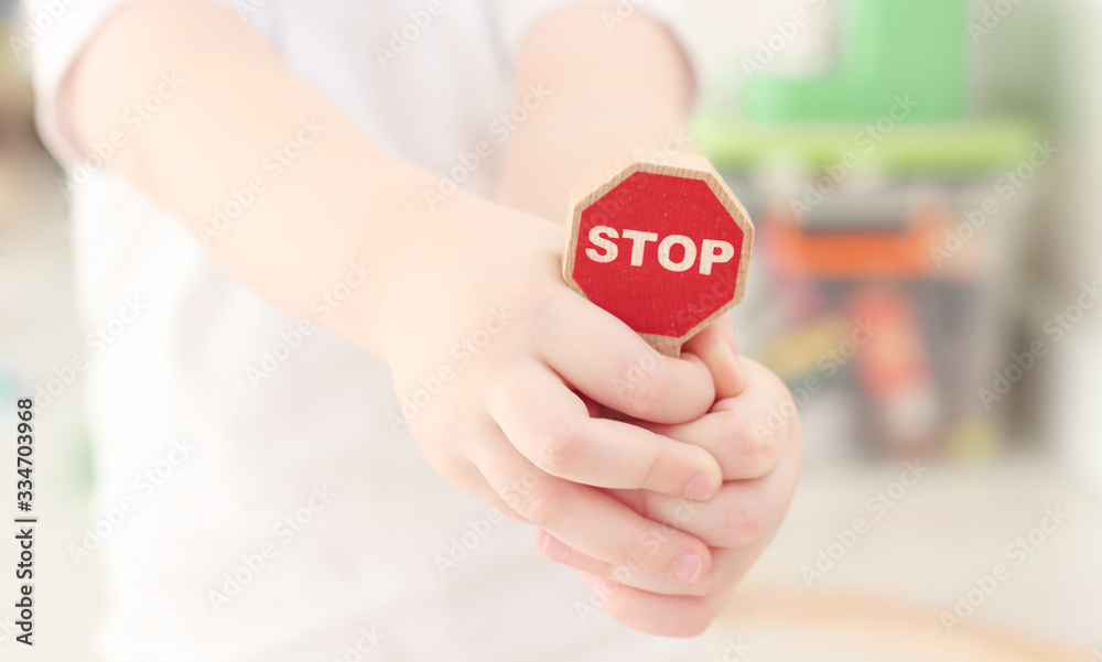 caucasian boy is clutching in palms and holding a close-up toy wooden ...