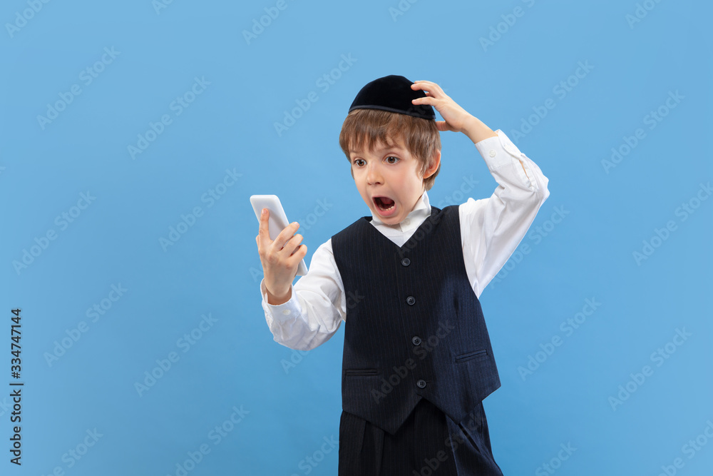 Shocked using phone. Portrait of a young orthodox jewish boy isolated ...