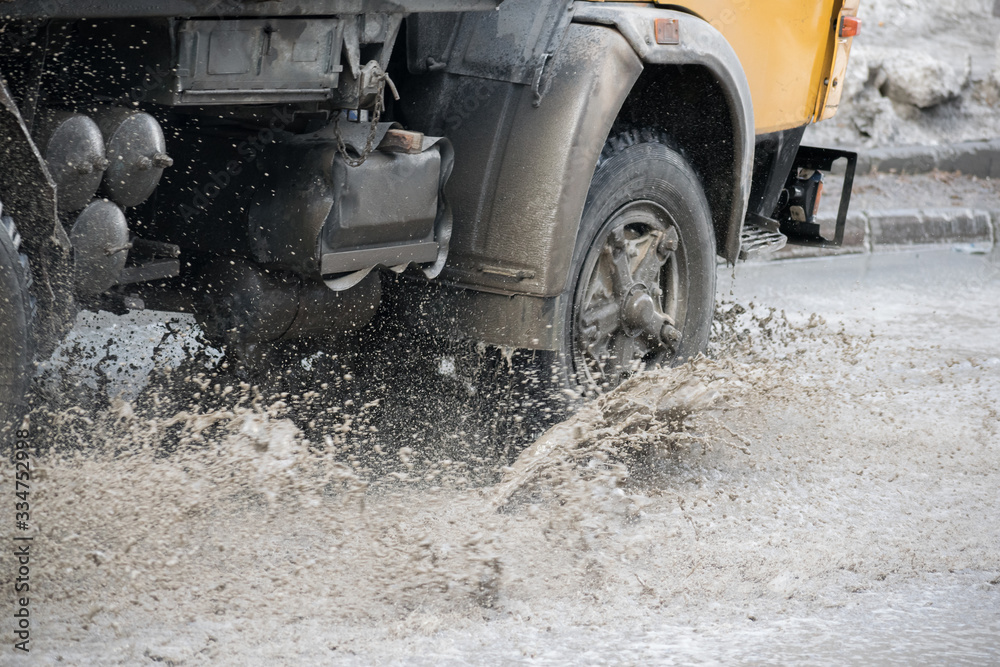 Car motion through big puddle of water splashes from the wheels on the ...