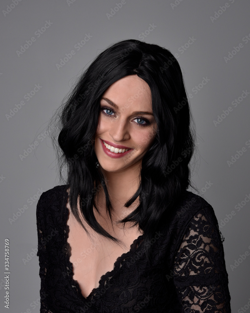 Close up portrait of a pretty, goth girl with dark hair posing in front ...