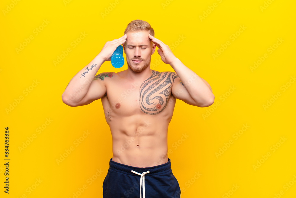 young blonde strong man looking concentrated, thoughtful and inspired ...