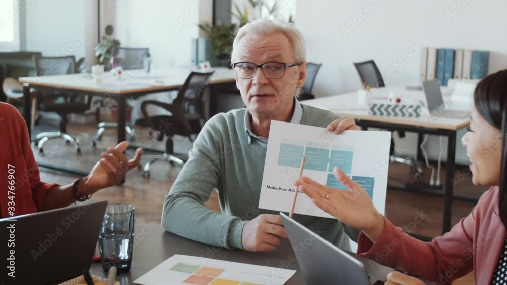 PAN shot of multiethnic colleagues of different age listening to ...