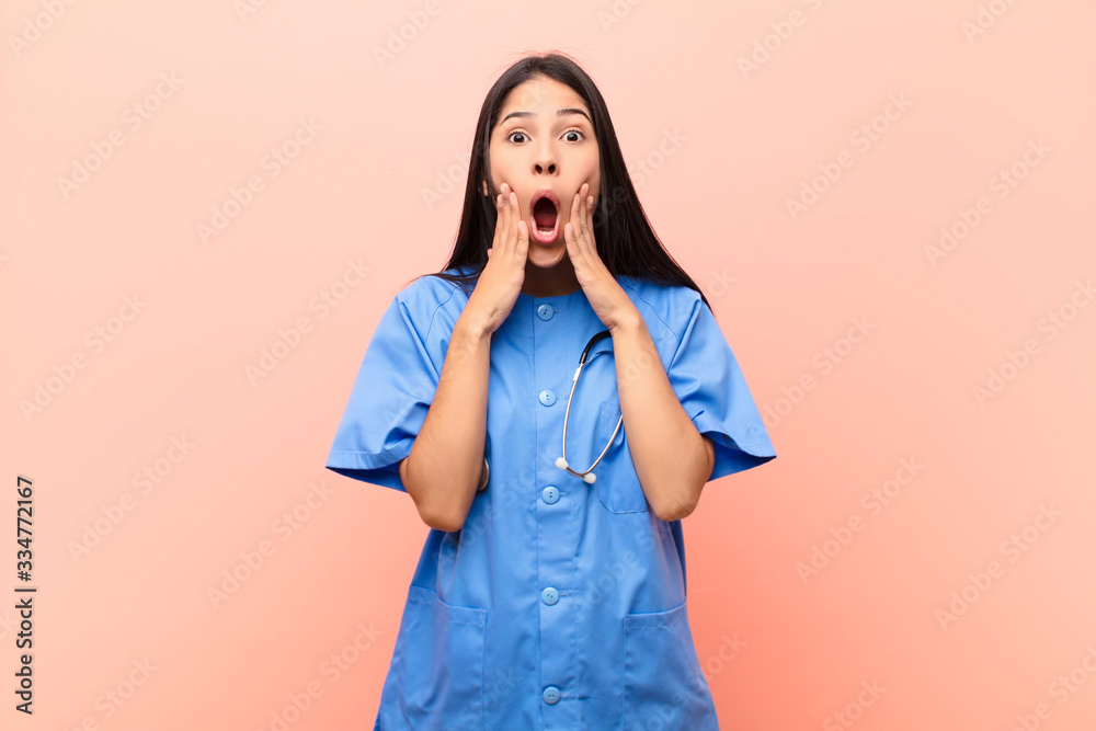 young latin nurse feeling shocked and scared, looking terrified with ...