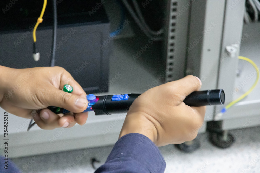 Closeup hand holding fiber optic cables with visual fault locator laser ...