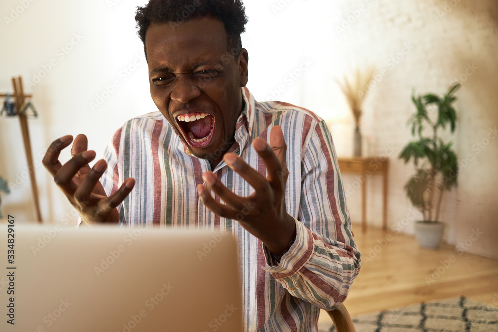 Negative human emotions. Indoor shot of angry depressed young African ...