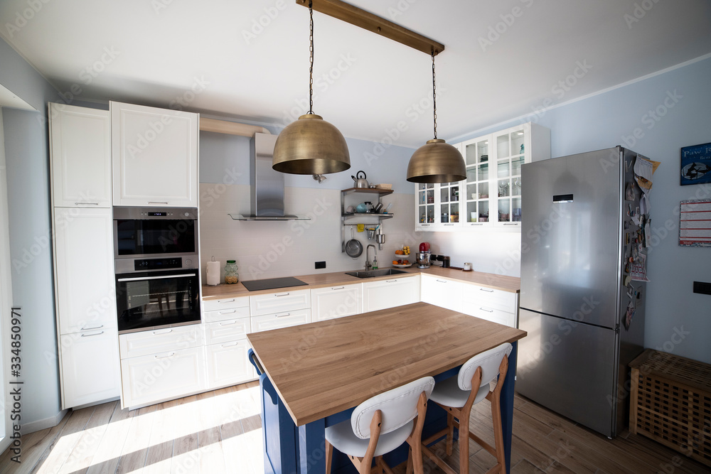 White, well lit, scandi styled kitchen with blue island and double ...