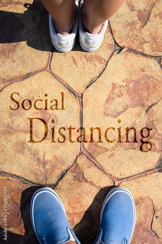 People stand on the road with the word social distancing in between ...