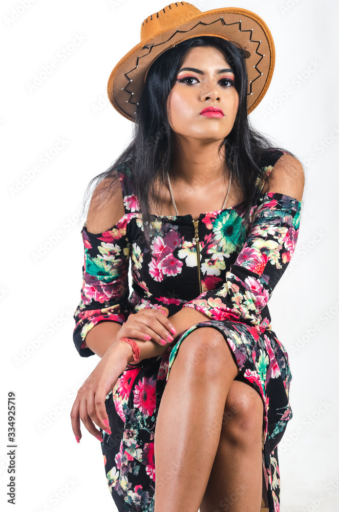Young woman in a floral pattern dress and wearing a cowboy hat sitting ...