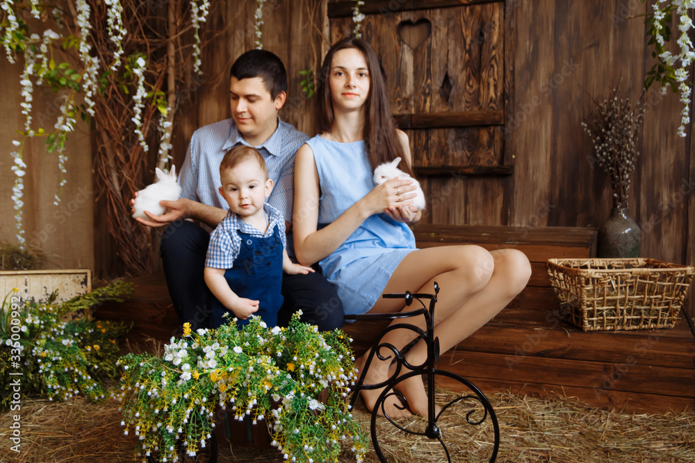 family in the village, with rabbits in their arms. little boy with mom ...