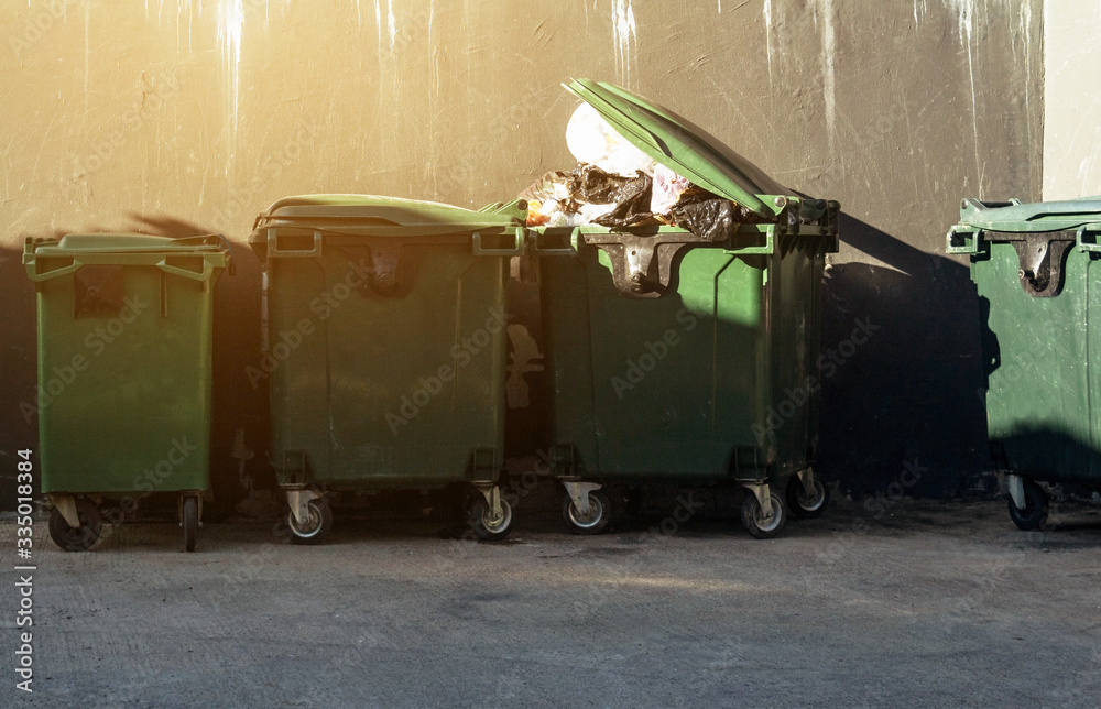 Trash can overflowing with garbage along a wall on a city street on a ...