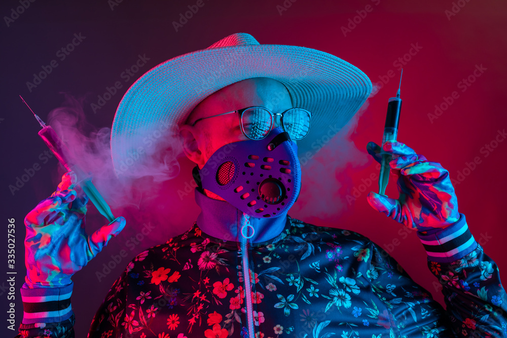 Strange man in medical respirator mask, glasses and hat holding two ...