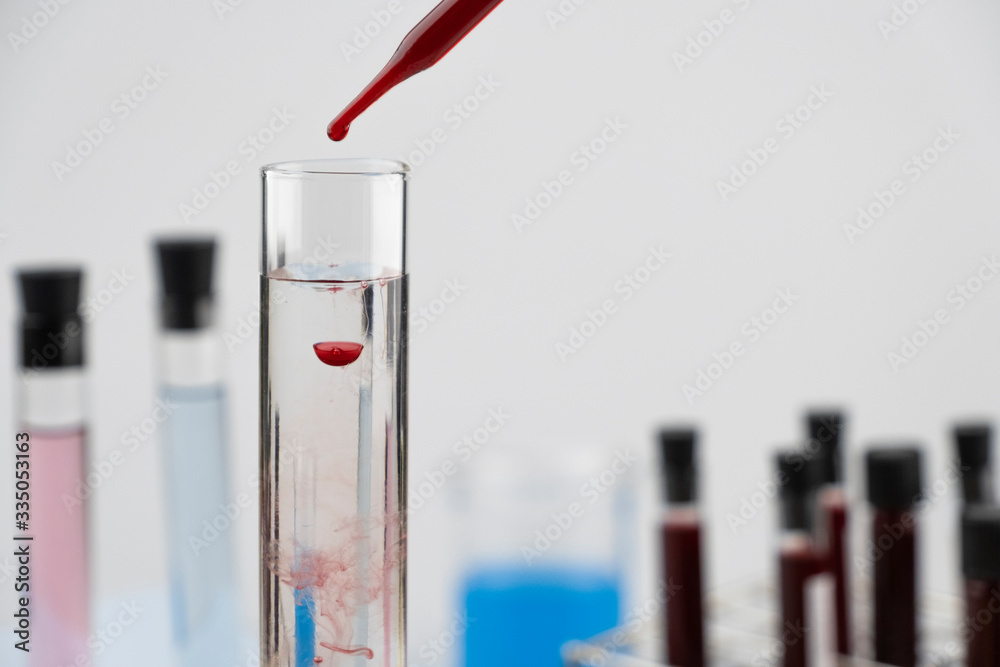 Clear science liquid in test tube with blood sample from pipette ...