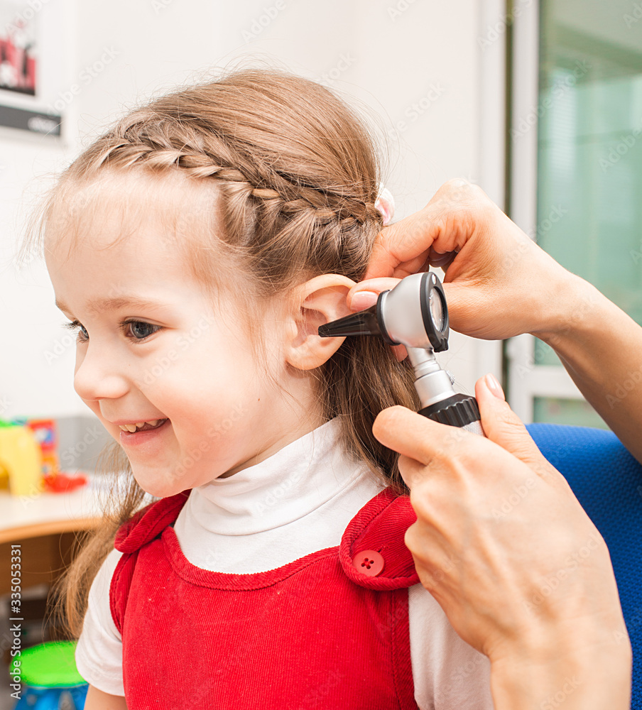Audiologist examining little girl ear , using otoscope, in doctors ...