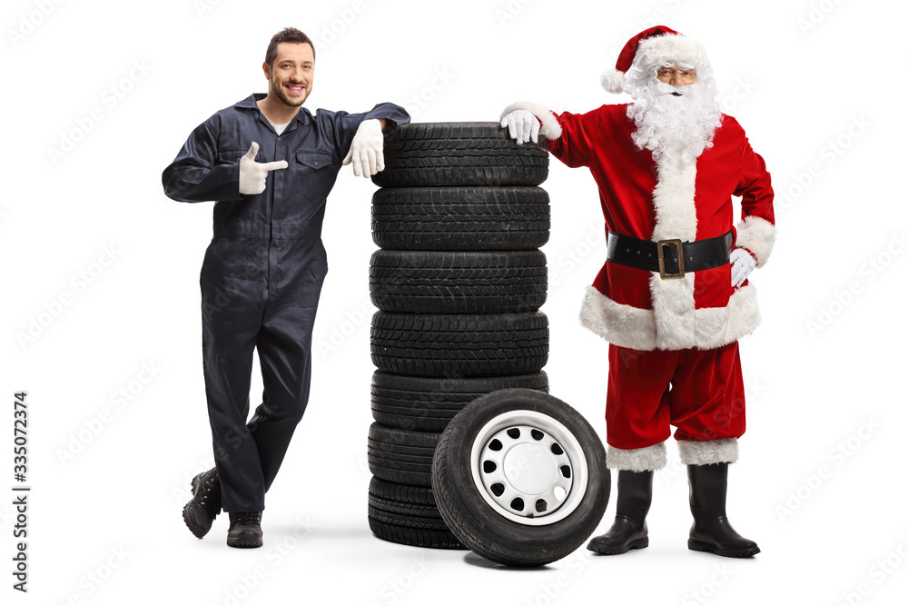 Auto mechanic pointing at a pile of tires and posing with Santa Claus ...