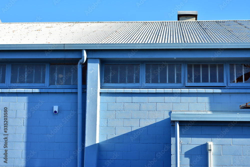 Back side of industrial building painted pale blue with windows with ...
